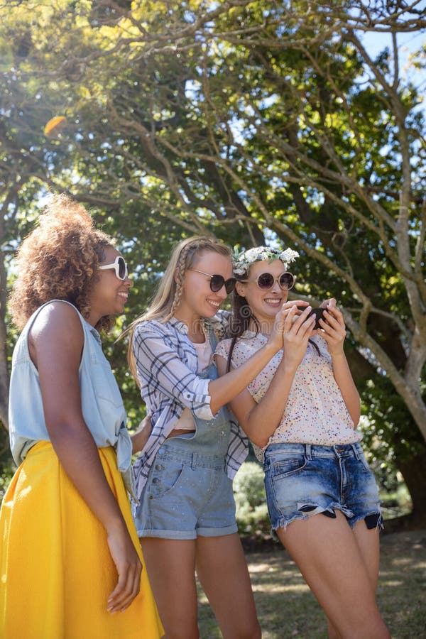 Female Friends Looking at Mobile Phone in Park Stock Image - Image of ...