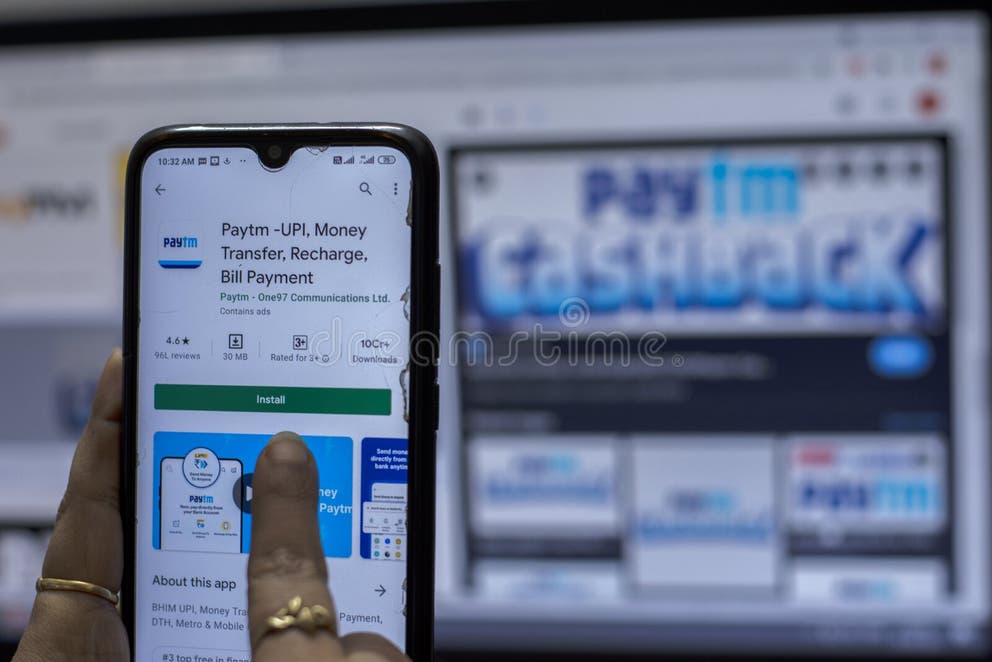 A Female Hand Holding a Android Smart Phone in Front of a Desktop ...