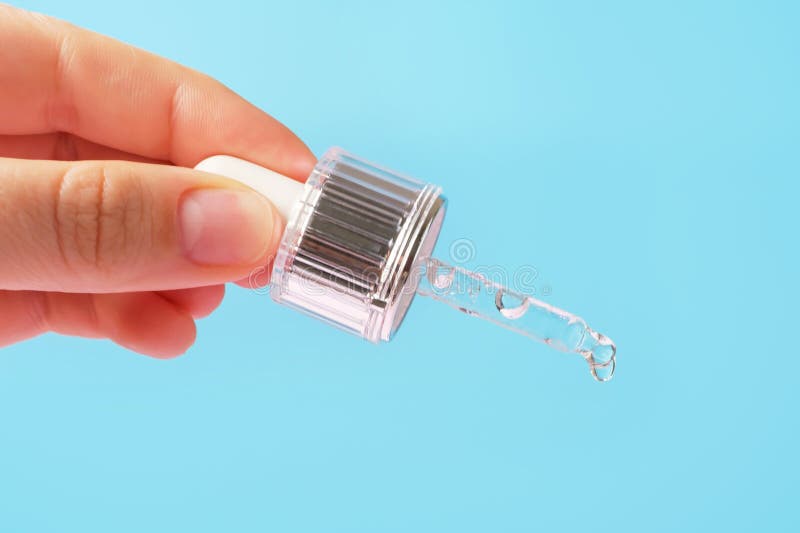 Female Hand Holding Dropper with Moisturizing Serum on Blue Background ...