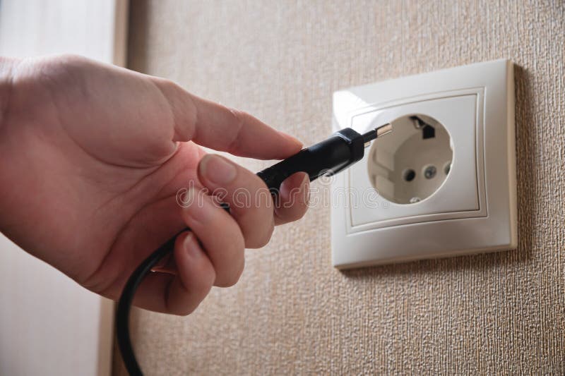 A Female Hand Inserts an Electric Plug into a Euro-format Socket Close ...