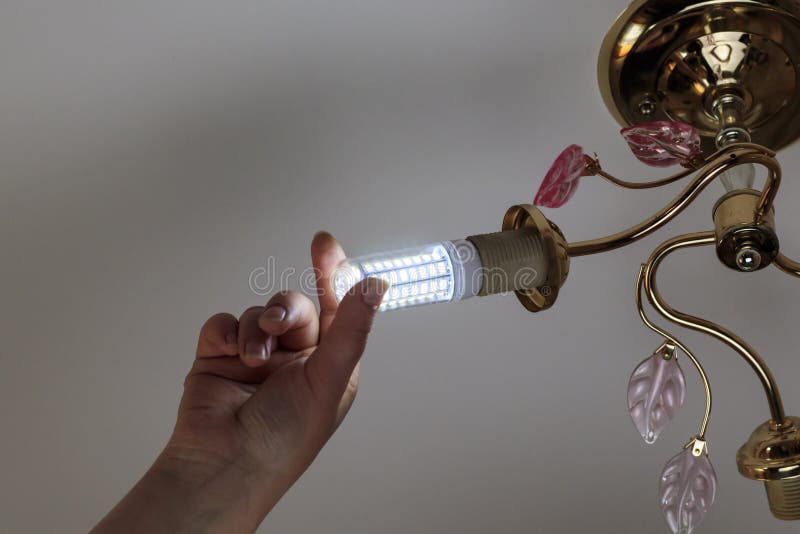 Female Hand Inserts a Light Bulb into the Threaded Socket. she is ...