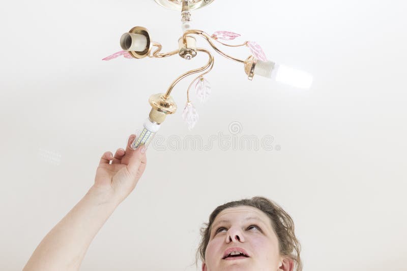 Female Hand Inserts a Light Bulb into the Threaded Socket. she is ...