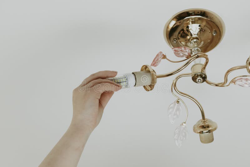 Female Hand Inserts A Light Bulb Into The Threaded Socket. Installation ...