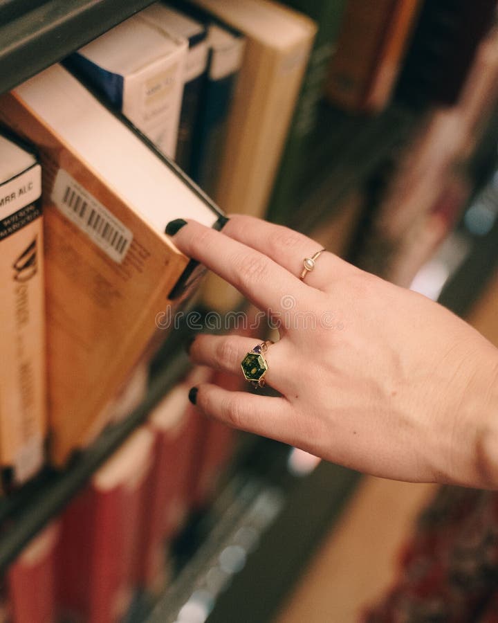 Female Hand Pulling Out a Green Book from the Library Shelf, Ring in Focus Stock Image - Image ...