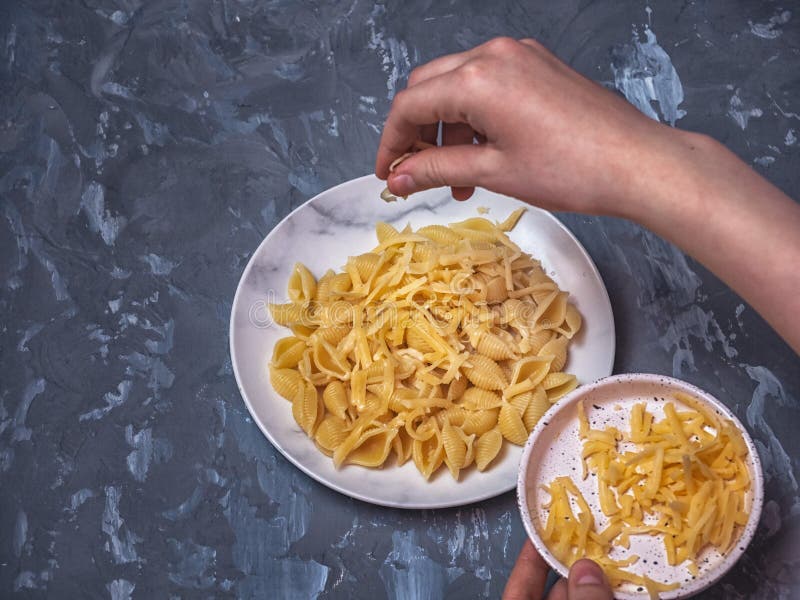 Female Hand Sprinkles with Grated Cheese Paste, Lying on a White Plate ...