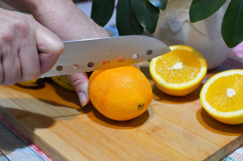 Female Hands Cutting an Orange in Half with a Sharp Knife Stock Photo ...