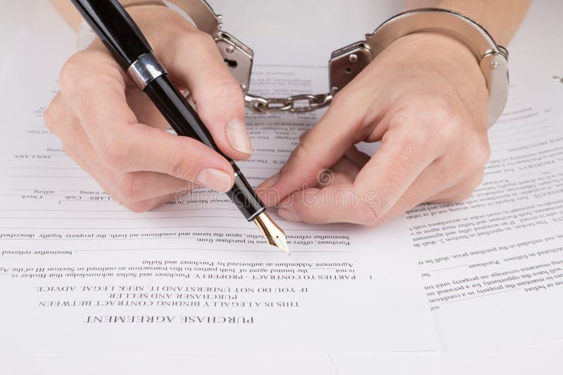 The Hands of the Criminal in Handcuffs Write with a Pen on Paper. Stock ...