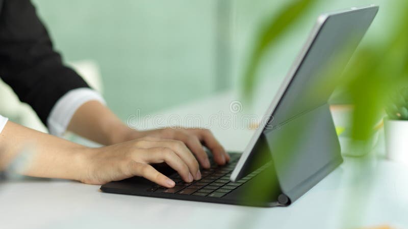 Female Hands Typing on Tablet Keyboard on White Table Decorated with ...