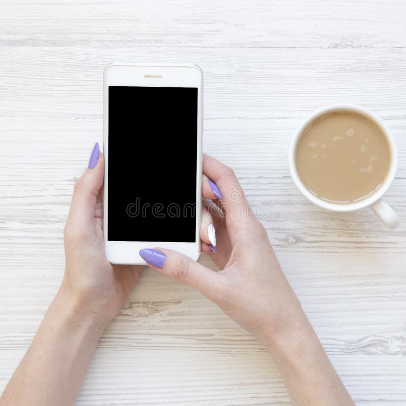 Female Hands Using Smartphone and Drinking Latte Over White Wooden ...