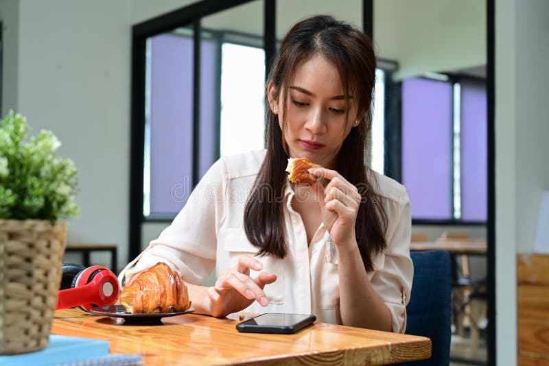 Female Having Breakfast and Using Smart Phone at Her Workplace. Stock ...