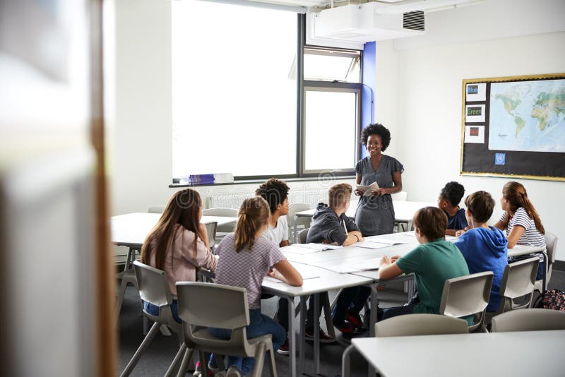 Female High School Tutor Standing by Table with Students Teaching ...