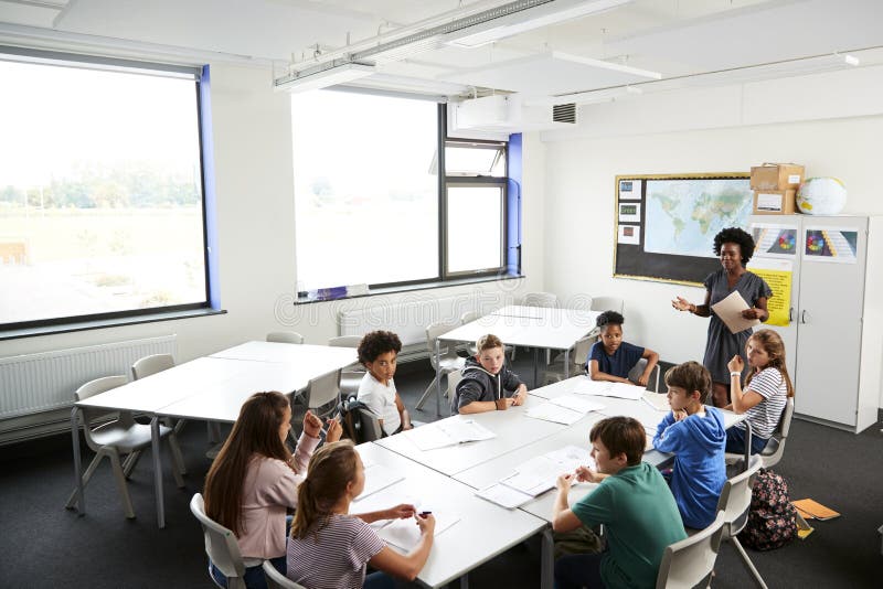 Female High School Tutor Standing by Table with Students Teaching ...