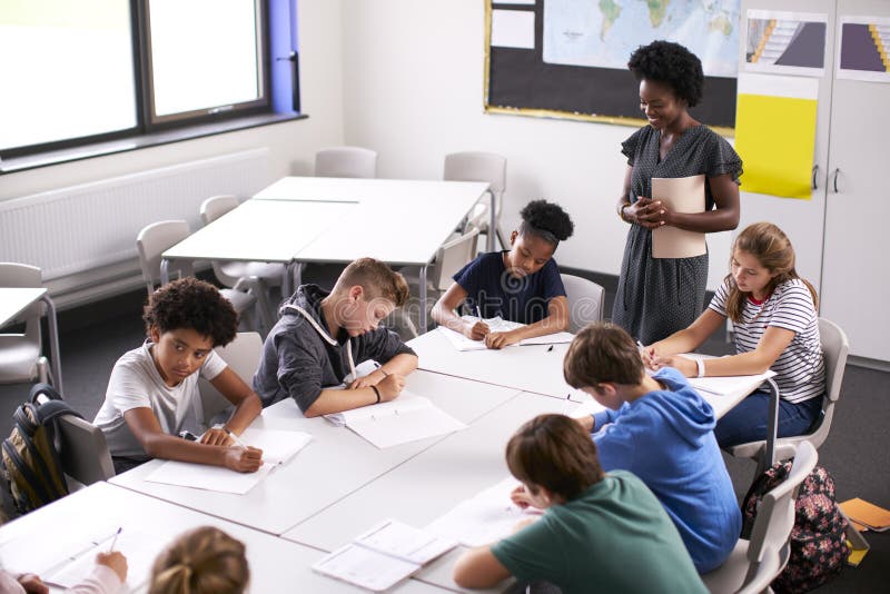 Female High School Tutor Standing by Table with Students Teaching ...