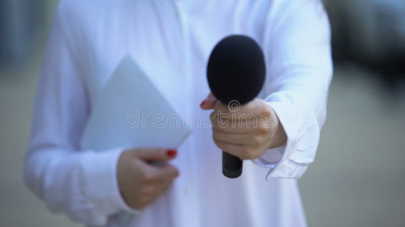 Female Journalist with Notebook Proposing Microphone, Interviewing ...