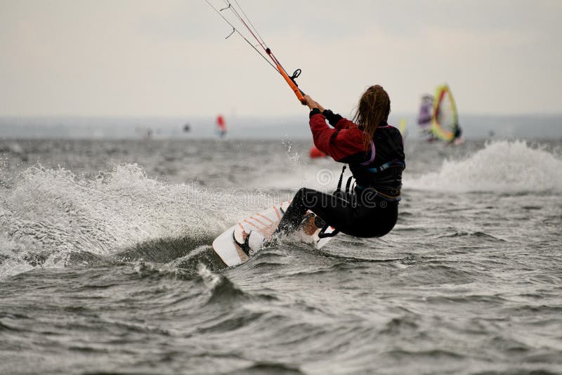 Female Kiteboarder Holds on To the Handle of the Kite on Her Surfboard ...
