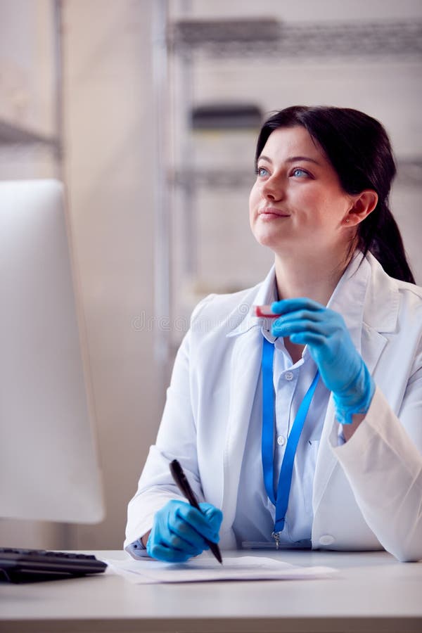 Female Lab Worker Wearing White Coat Recording Blood Test Results on ...