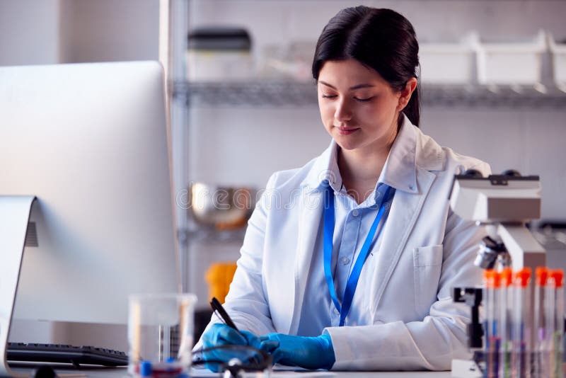 Female Lab Worker Wearing White Coat Recording Test Results on Computer ...