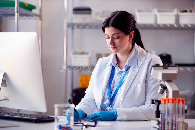 Female Lab Worker Wearing White Coat Recording Test Results on Computer ...