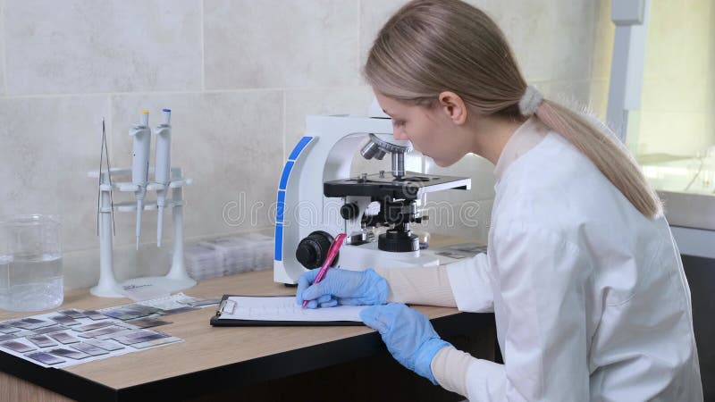 A Female Laboratory Assistant Studies Microorganisms by Looking through ...