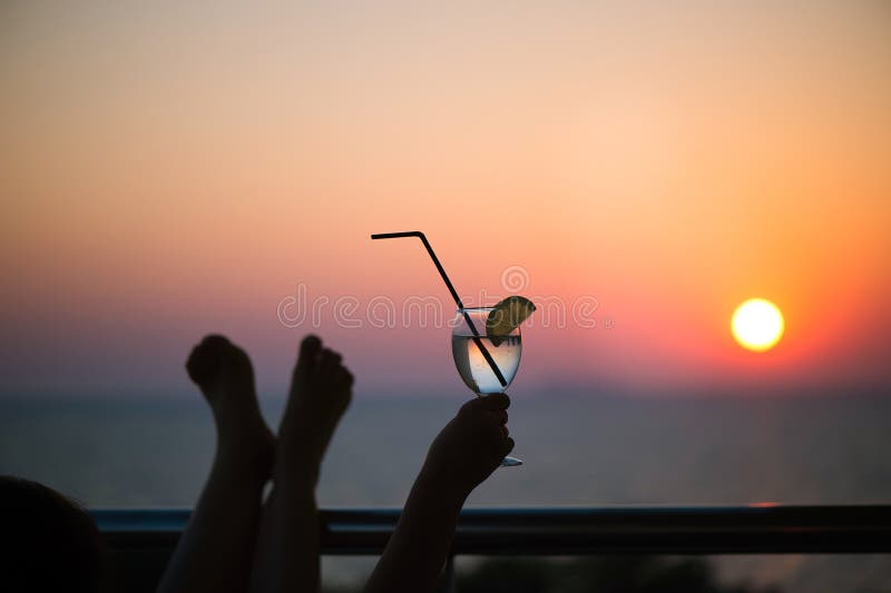 Female Legs and Glass with Cocktail in the Hand on Sunset Background ...