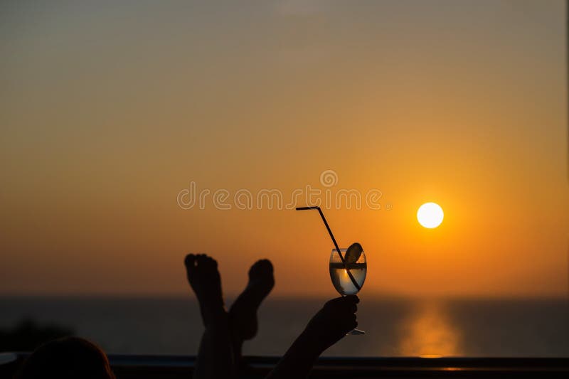 Female Legs and Glass with Cocktail in the Hand on Sunset Background ...