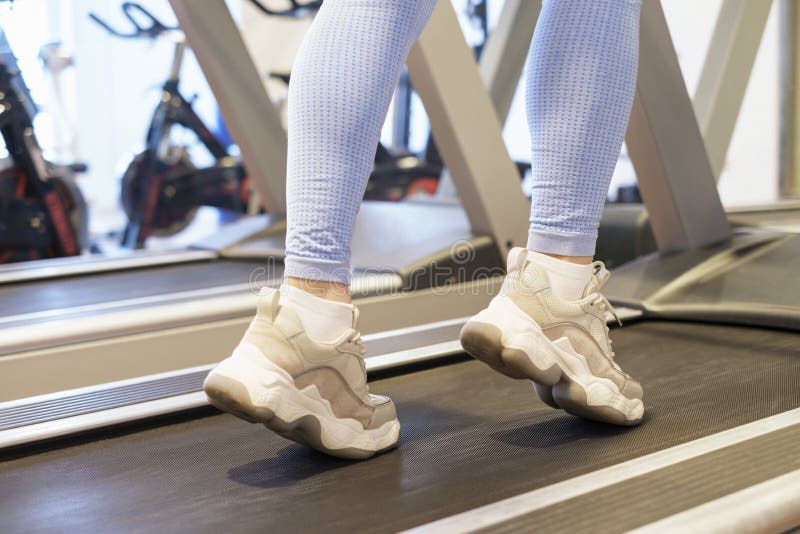 Female Legs in Sneakers Run on a Treadmill Close-up, Side View. Stock ...