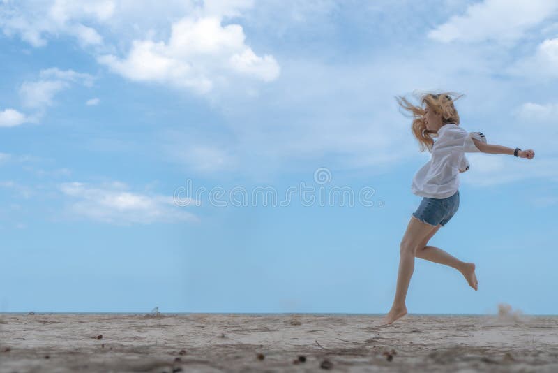 Female Making Jump on Sandy Beach with Blue Sky Stock Image - Image of ...