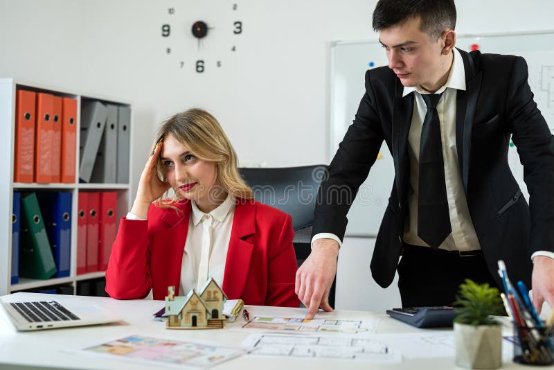 A Female Manager Shows a Client a Plan for Housing Construction in the ...