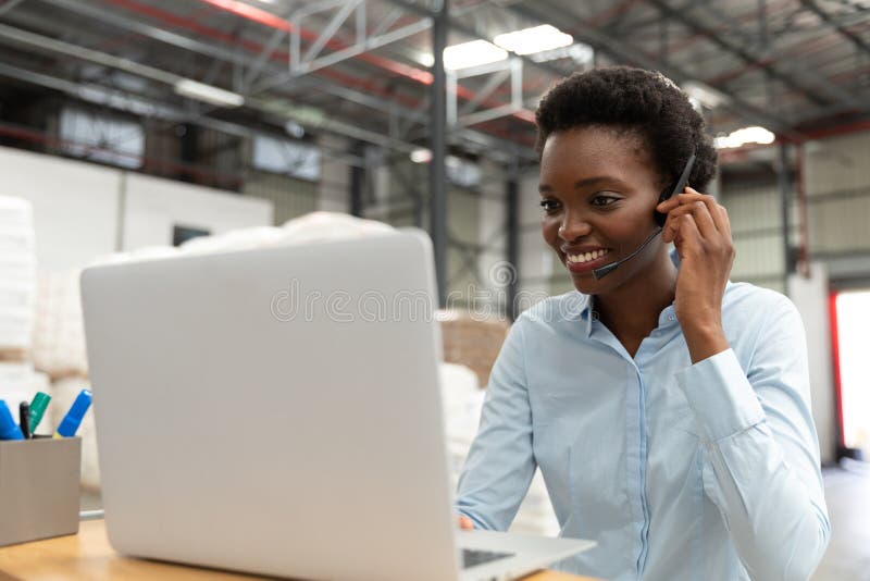 Female Manager Talking on Headset while Using Laptop at Desk in ...