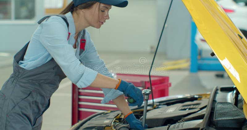 Female Mechanic Working on a Vehicle in a Car Service. Woman Fixing the ...