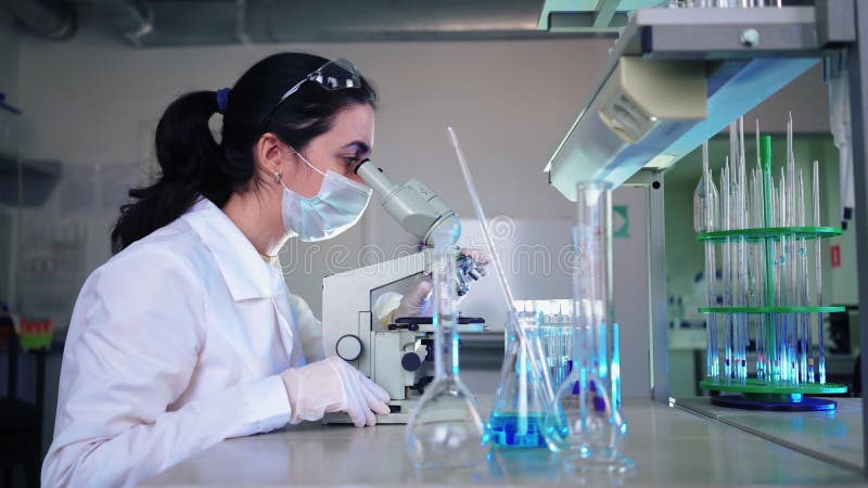 Female Microbiologist Looking into Microscope in Medical Science ...