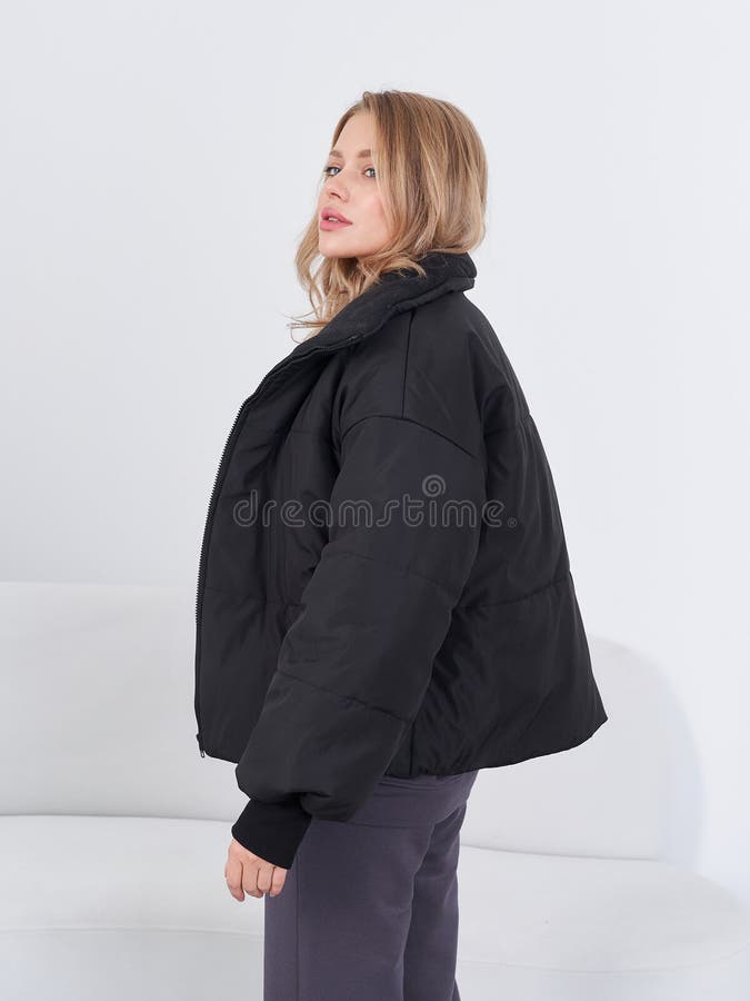 Female Model in a Black Puffer Jacket with a High Collar, Adjusting the ...