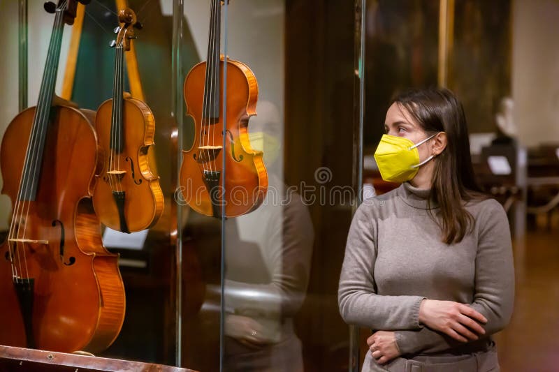 Female Museum Visitor in Mask Examining Ancient Musical Instruments ...