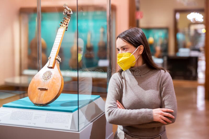Female Museum Visitor in Mask Examining Ancient Musical Instruments ...