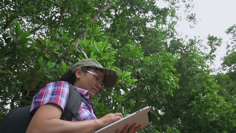 Female Nature Researcher with Backpack Working on Digital Tablet while ...