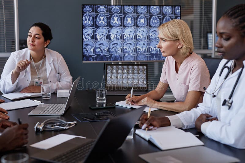 Female Neurologist Writing Notes while Analyzing Brain X Ray Scans at ...