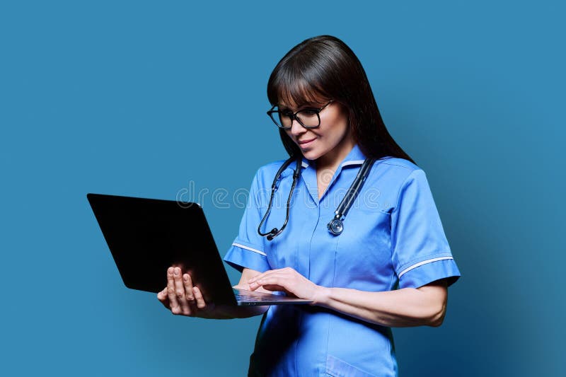 Female Nurse Using Laptop, Profile View on Blue Studio Background Stock ...