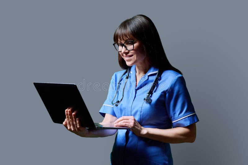 Female Nurse Using Laptop, Profile View on Gray Studio Background Stock ...
