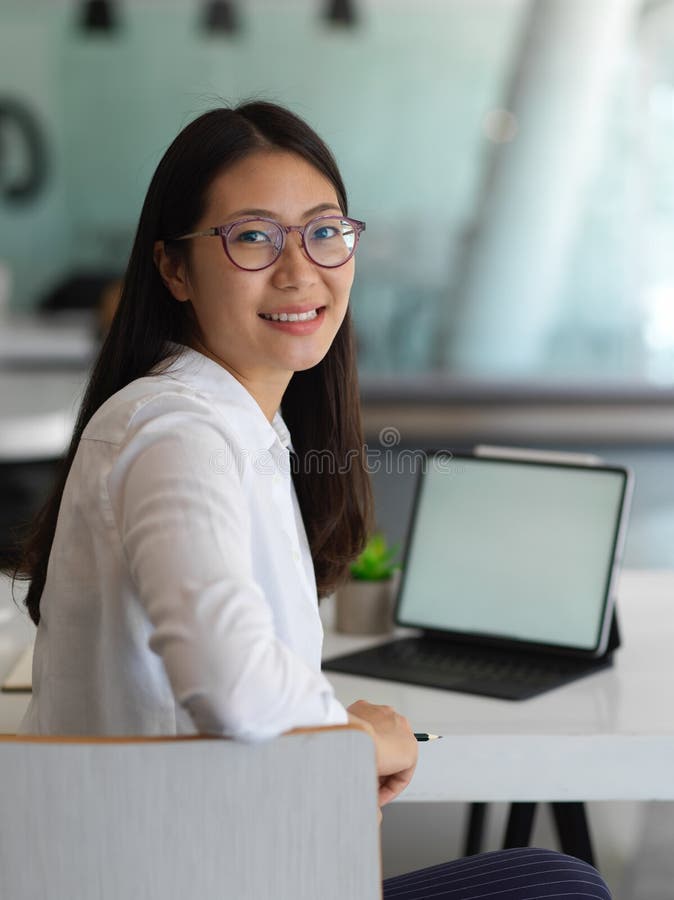 Female Office Worker Smiling and Looking into Camera while Working with ...