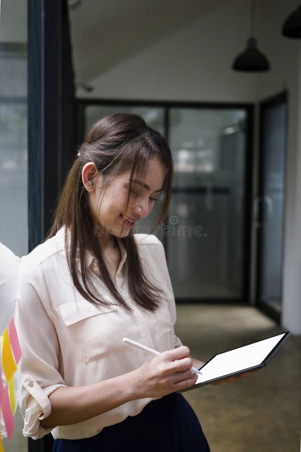 Female Office Worker Using Digital Tablet while Standing in Workplace ...
