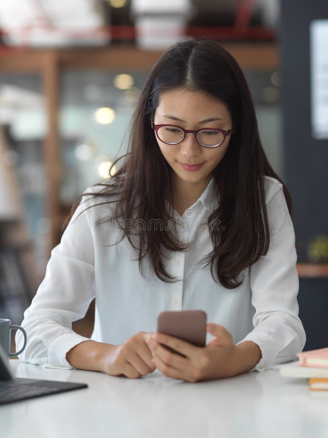 Female Office Worker Using Smartphone while Relaxing in Office Room ...