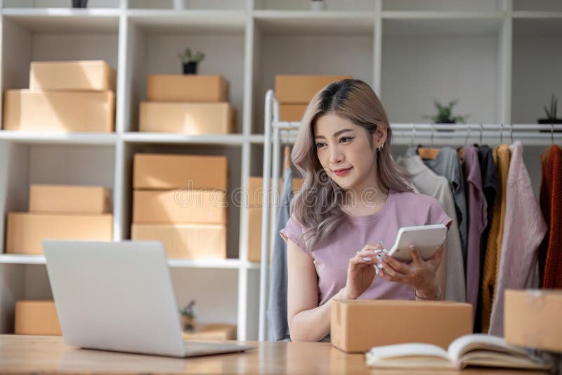 Female Online Seller Preparing Delivery Items and Using Calculator To ... Female Online Seller Preparing Delivery Items and Using Calculator To ...