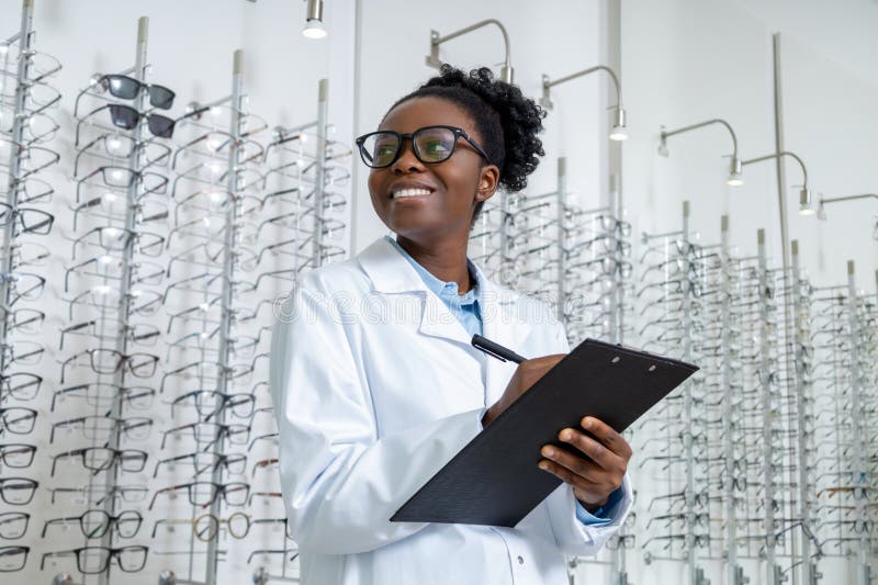 Female Optician in Lab Coat Making Notes and Smiling Stock Photo ...