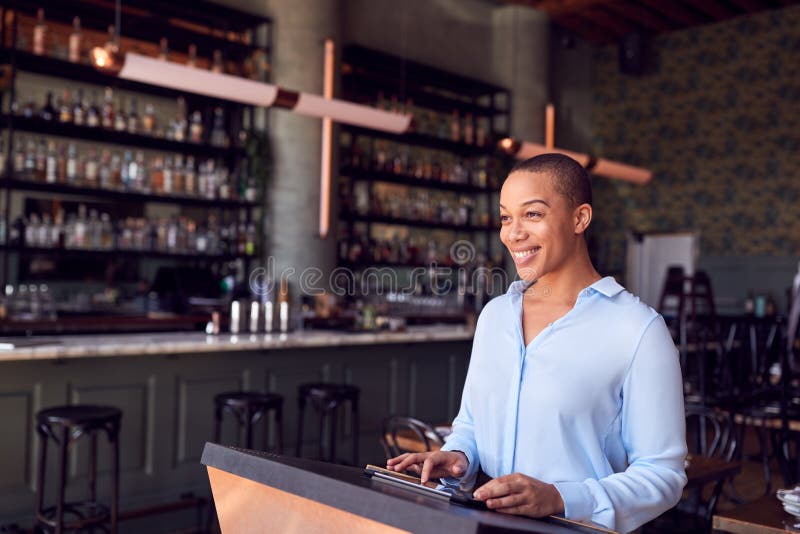 Female Owner of Restaurant Bar Standing at Counter Using Digital Tablet ...