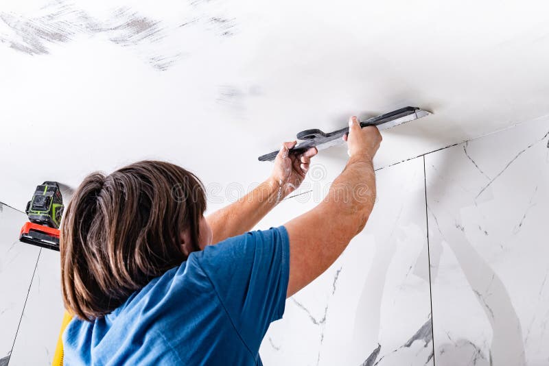 Female Painter Applying Putty To Ceiling. Stock Image - Image of ...