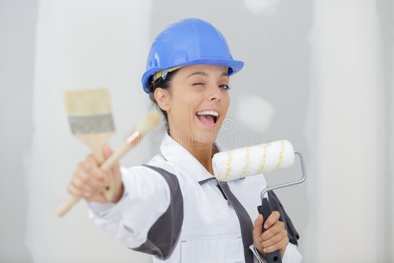Female Painter Decorator Holding Brushes and Roller and Winking Stock ...