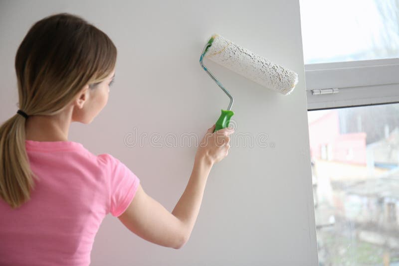 Female Painter Using Roller for Refurbishing Color of Wall Indoors ...