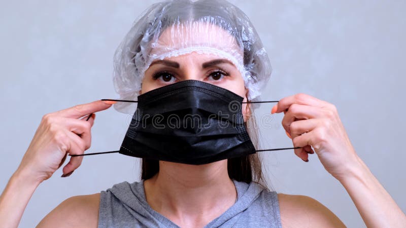 Female Patient in a Disposable Cap Puts on a Black Protective Mask ...