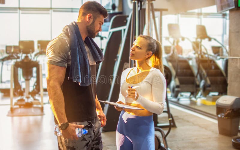 Female Personal Trainer Discussing Exercise Progress with Male Client ...