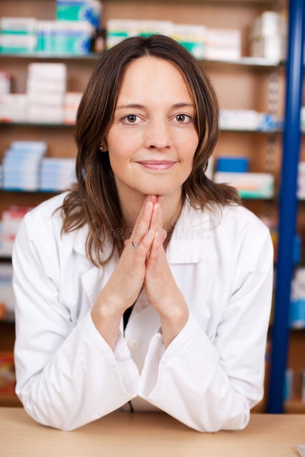 Female Pharmacist with Hands Clasped at Pharmacy Counter Stock Image ...